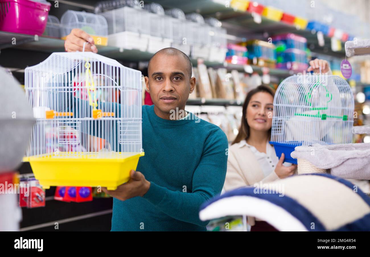 Man chooses bird cage at pet store Stock Photo - Alamy