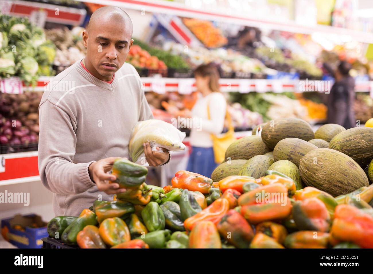 Latin man choosing sweet pepper and woman near choosing other ...