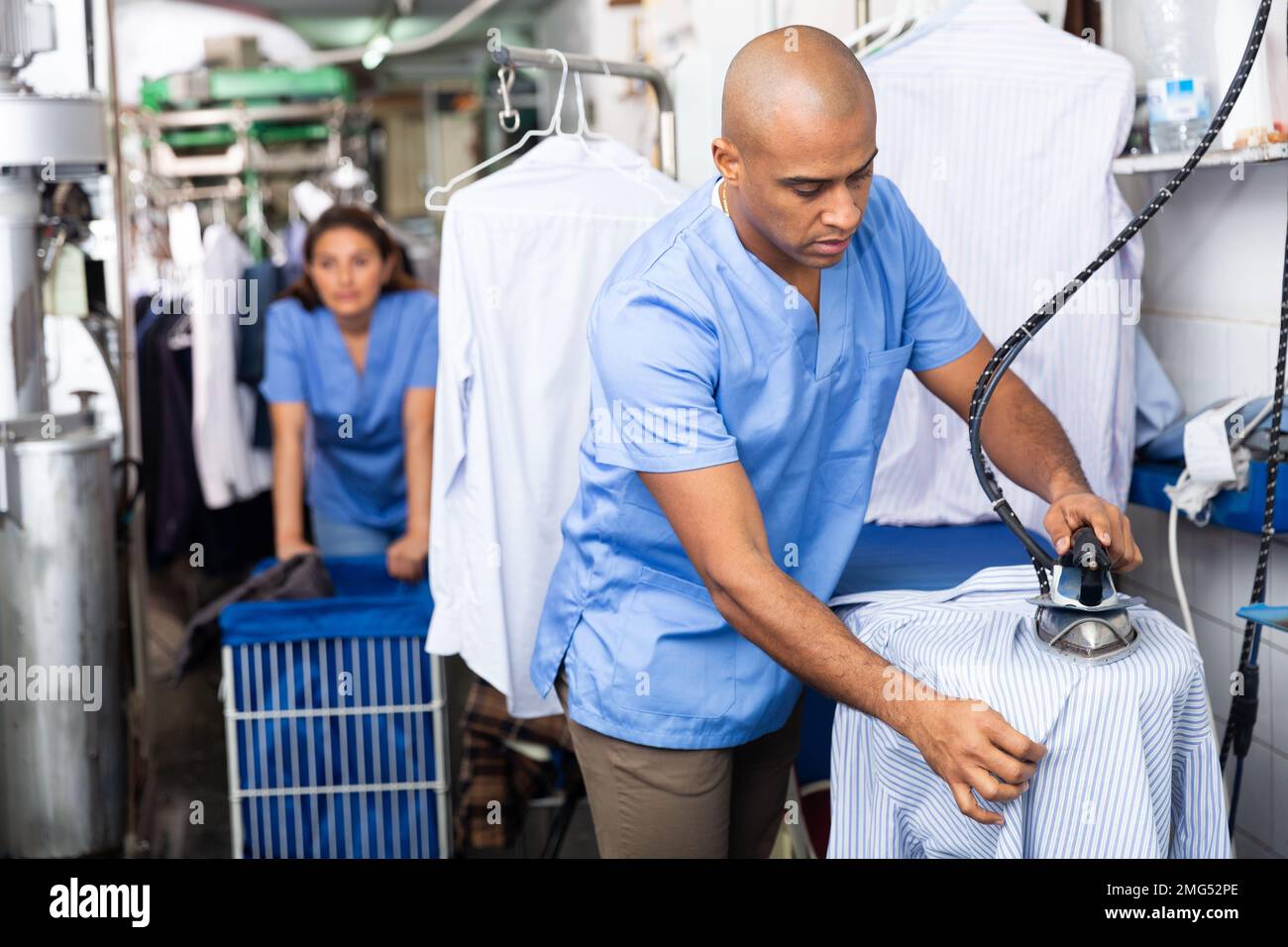 Laundry worker ironing clean clothes in dry cleaning salon Stock Photo ...