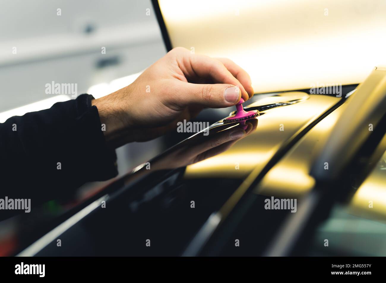 Close-up shot of unrecognisable man hand removing small dent in car ...