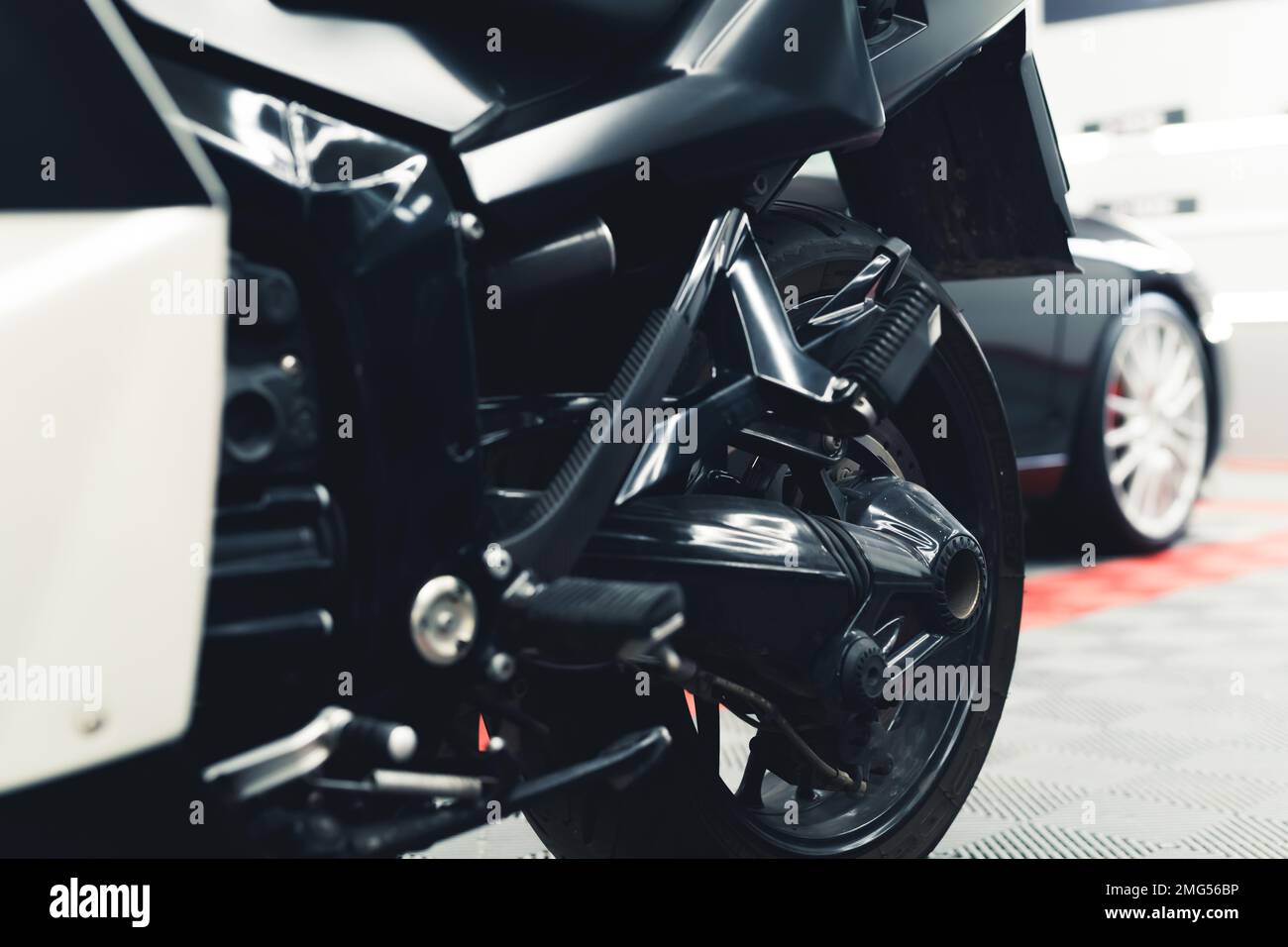 Low angle close-up shot of wheel of black motorcycle. Car salon. Garage ...