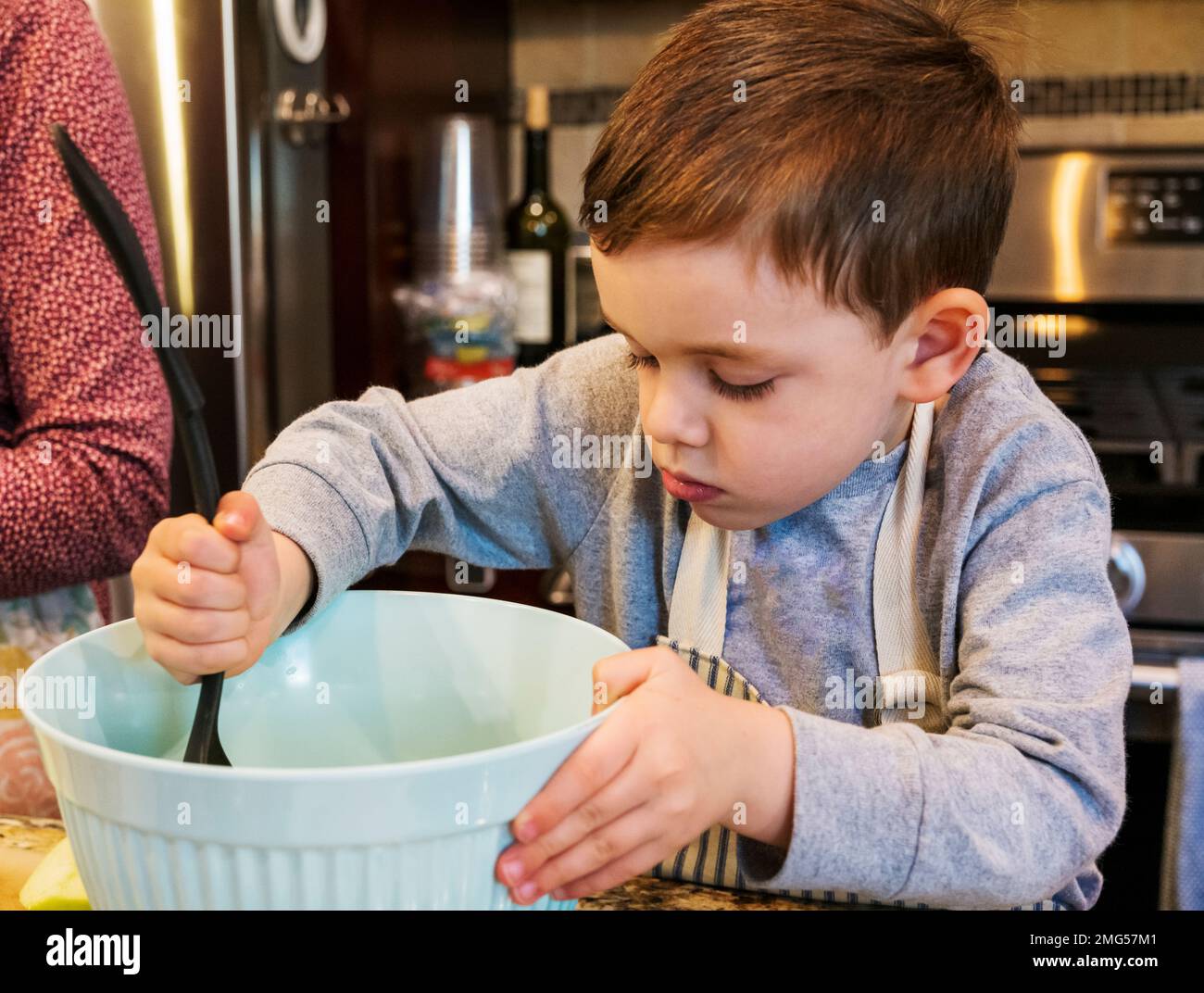 Three year old boy helping grandmother bake a Thanksgiving holiday ...