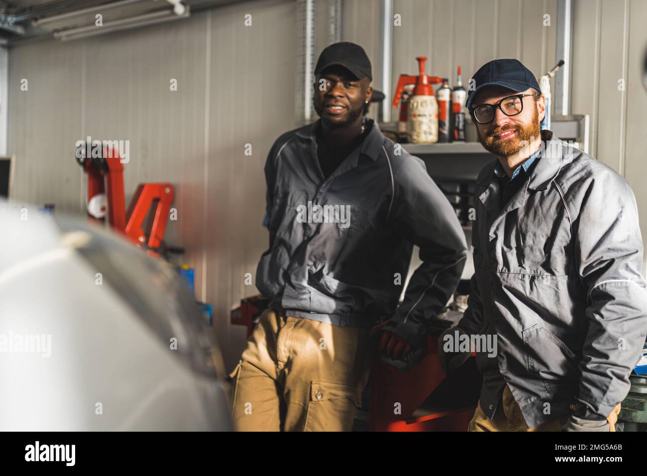 Medium shot of black and white mechanics posing for a picture and ...