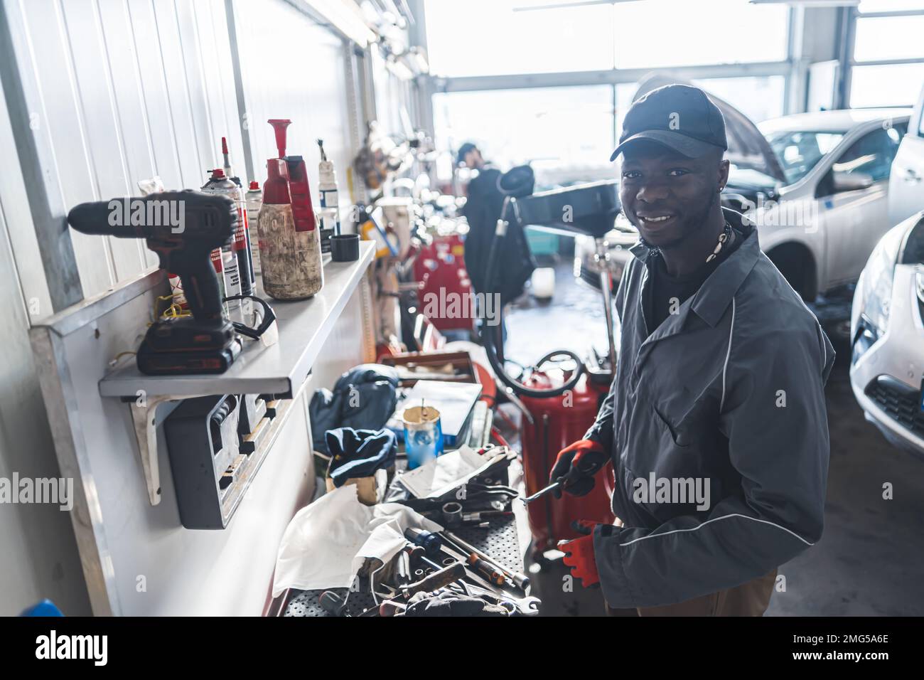 Medium shot. A black mechanic working by a wokbench, looking at the ...
