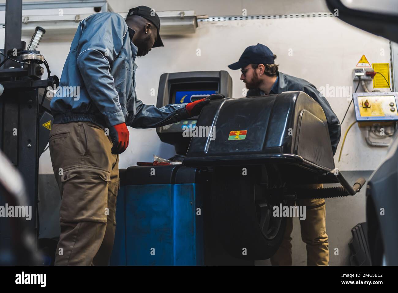 Low angle shot of black and white mechanics working by the computer in ...