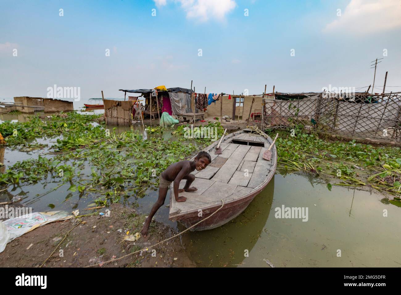 A boy plays near a boat by the flooded banks of the River Ganges in ...