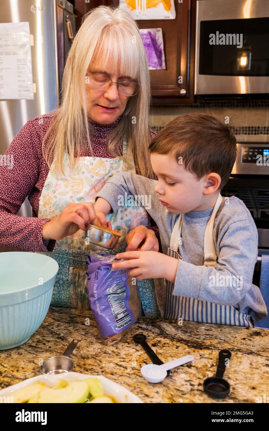 Three year old boy helping grandmother bake a Thanksgiving holiday ...