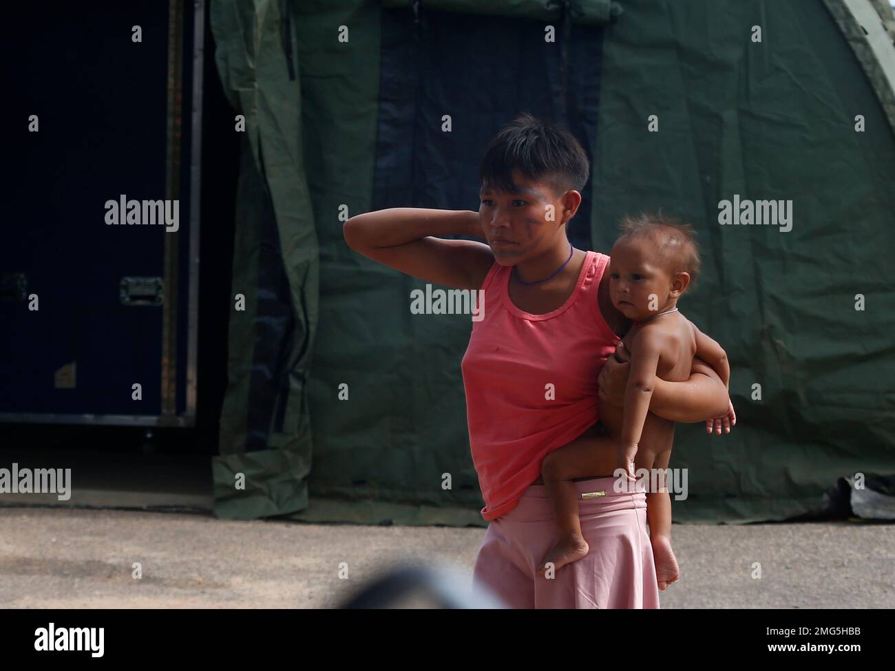 A Yanomami Indigenous carrying a baby, walks next to an Army field ...