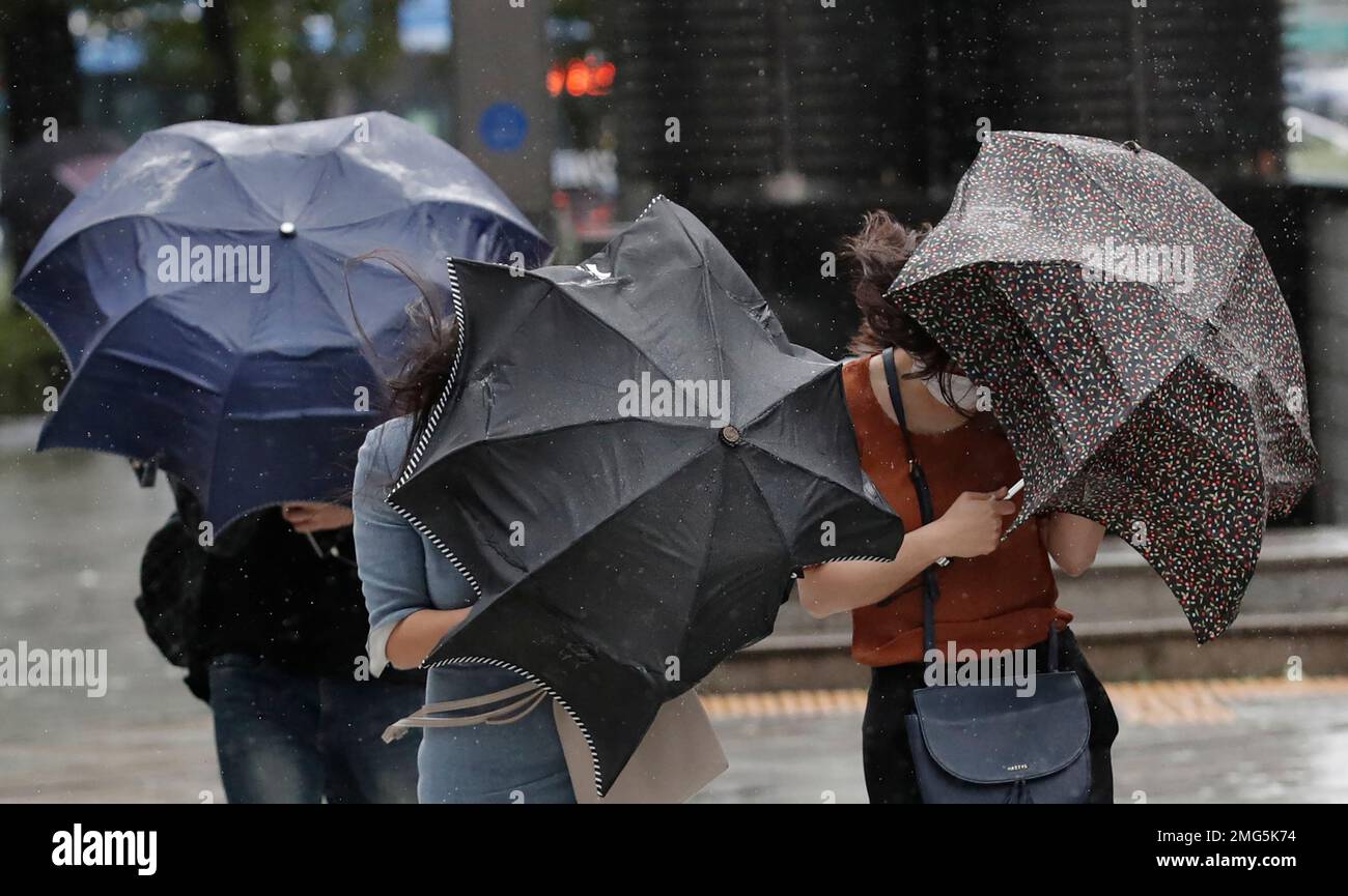 People struggle with their umbrellas against strong wind and rain in ...