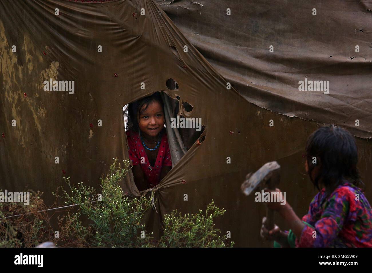 A nomadic girl talks to her sister from a hole in a ripped tent during ...