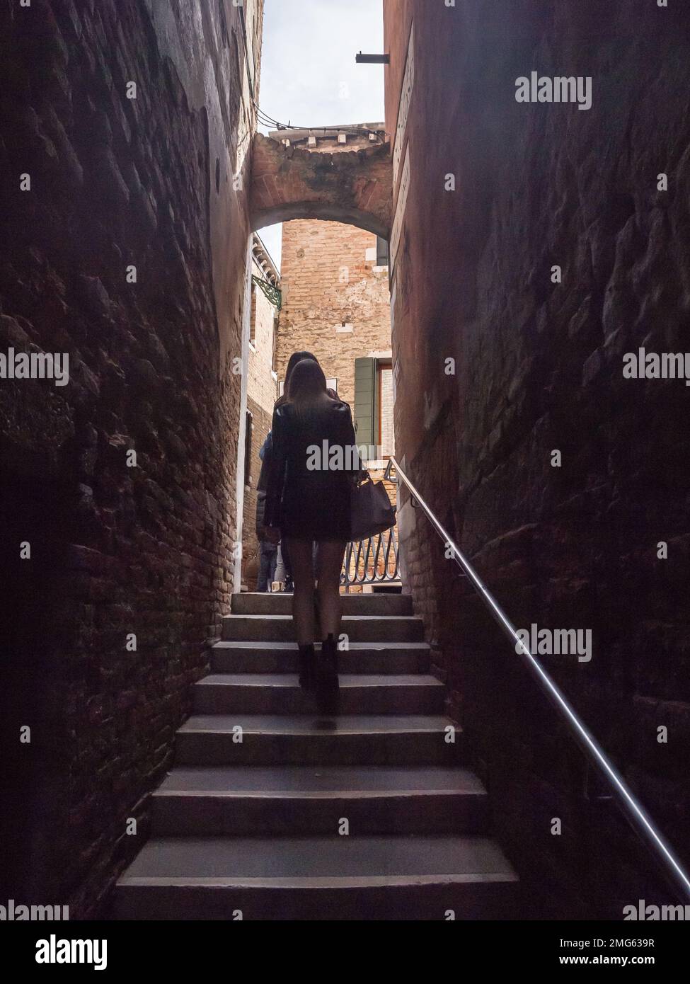 Woman climbing steps in alleyway in Venice Stock Photo - Alamy