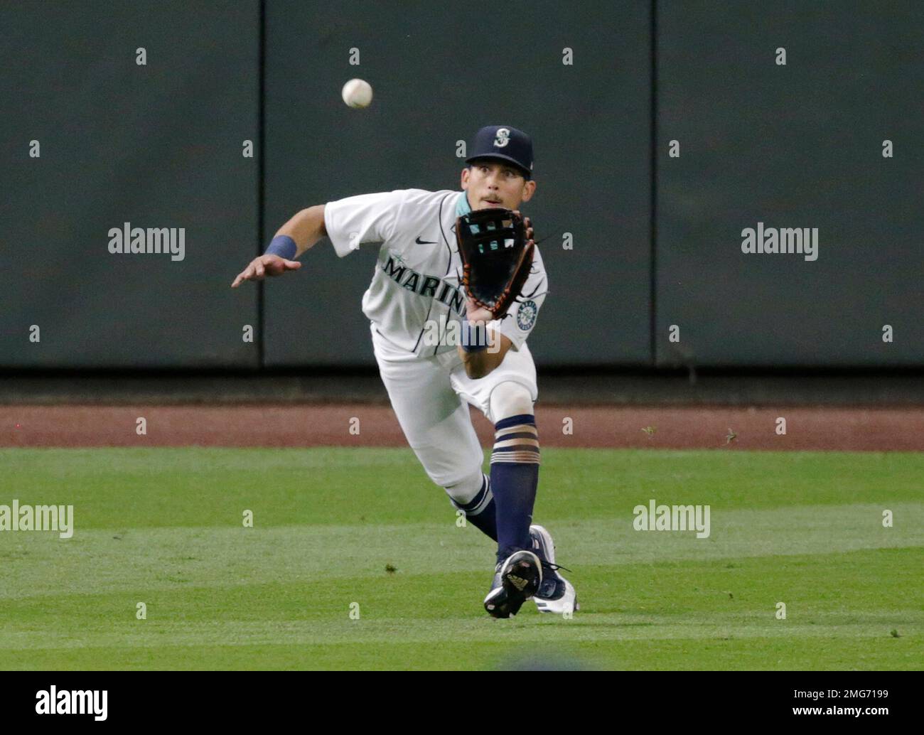 Seattle Mariners left fielder Sam Haggerty reaches to catch a fly ball ...