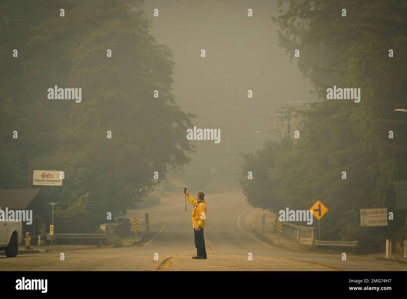 A firefighter takes a measurement in the middle of Highway 9 as smoke ...