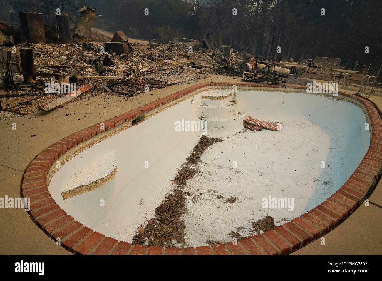 Debris is strewn in an empty swimming pool of a wildfire-ravaged home ...
