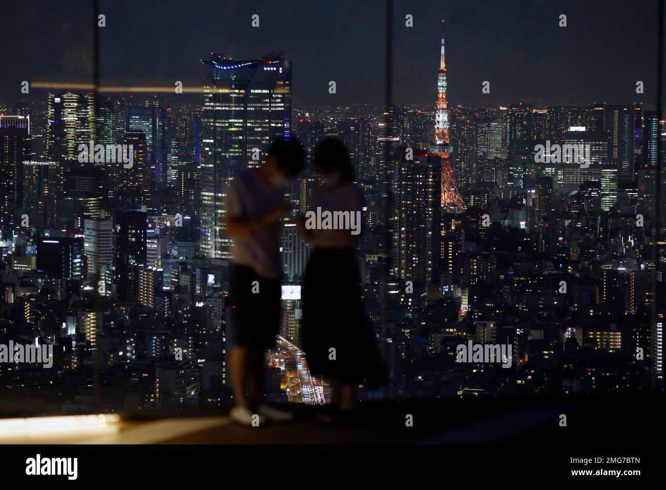 People visit a rooftop observation deck as Tokyo Tower is seen in the ...