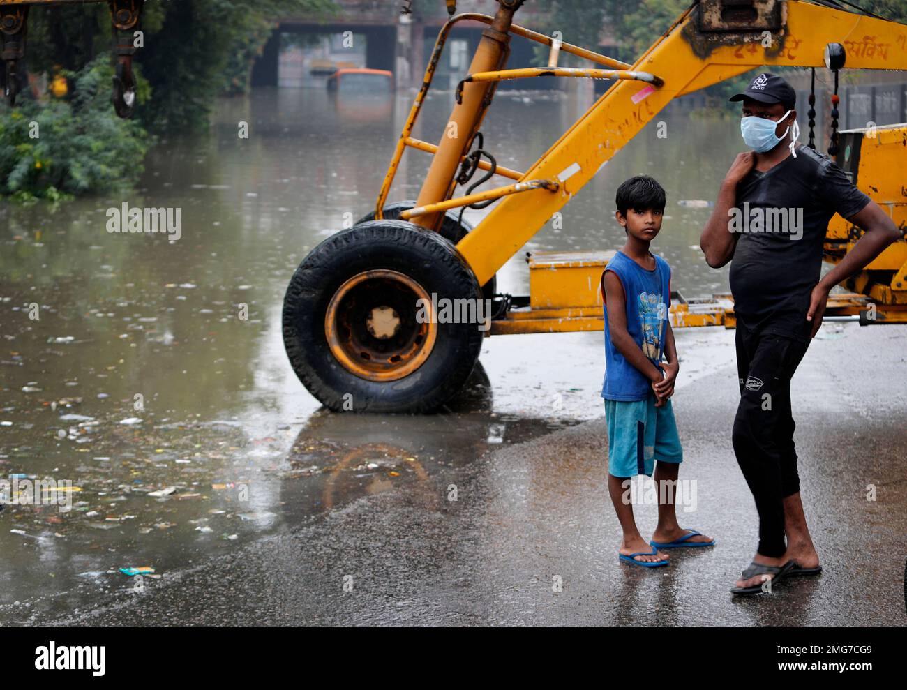 Passersby look at submerged vehicles in a flooded underpass following ...