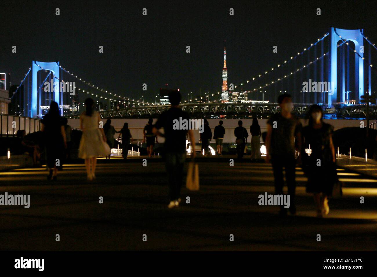 People wearing masks walk with the Tokyo Tower and Rainbow Bride ...