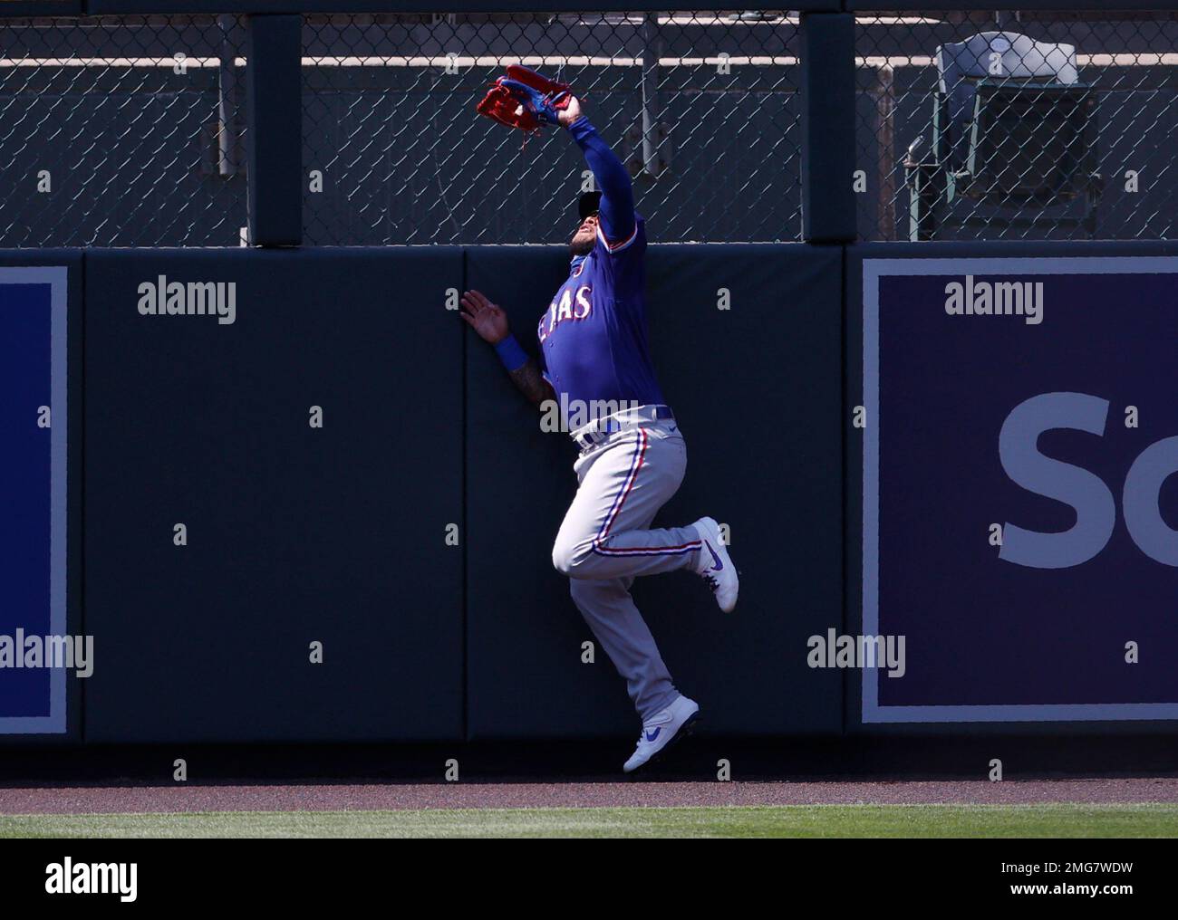 Texas Rangers left fielder Willie Calhoun hits the fence as he pulls in ...