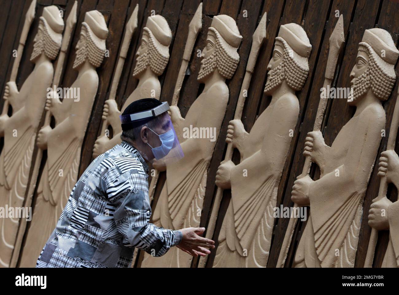 A Parsi man wearing mask as a precaution against the coronavirus prays ...