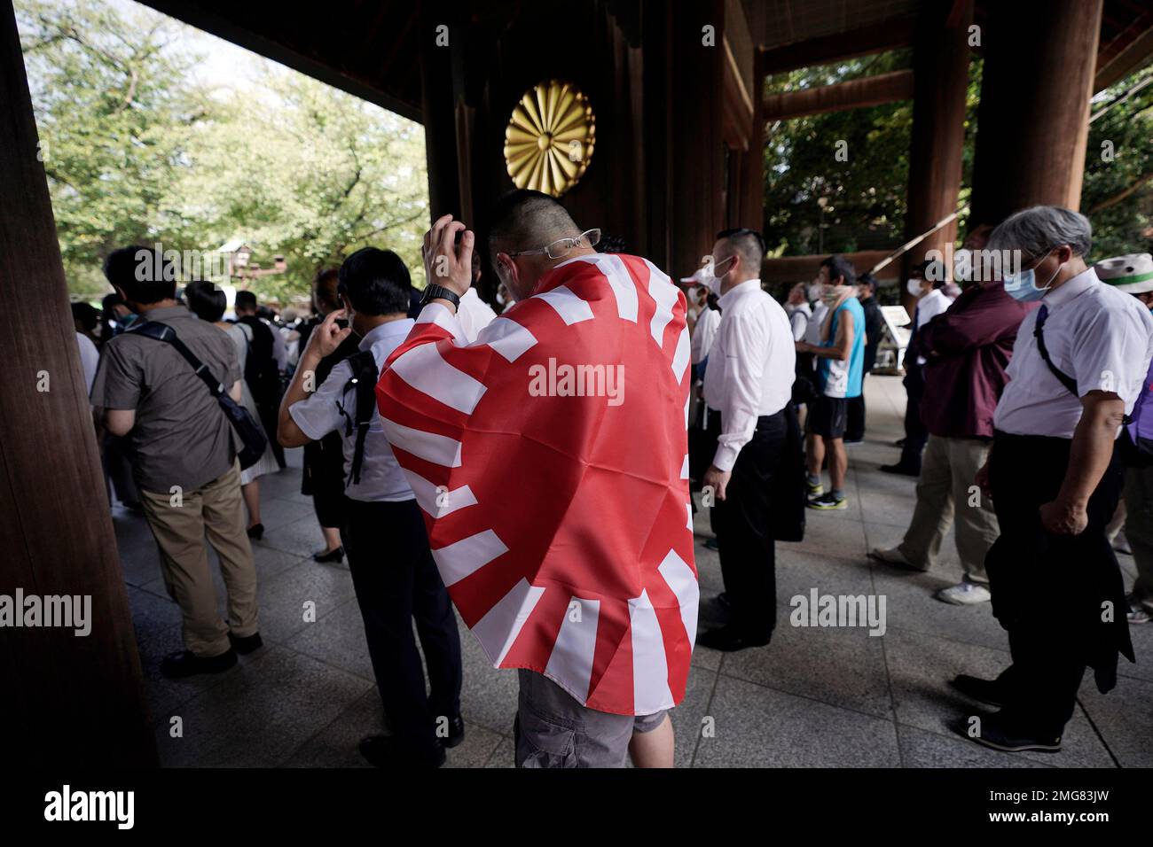 One of visitors carries a rising sun flag as he enters Yasukuni Shrine ...