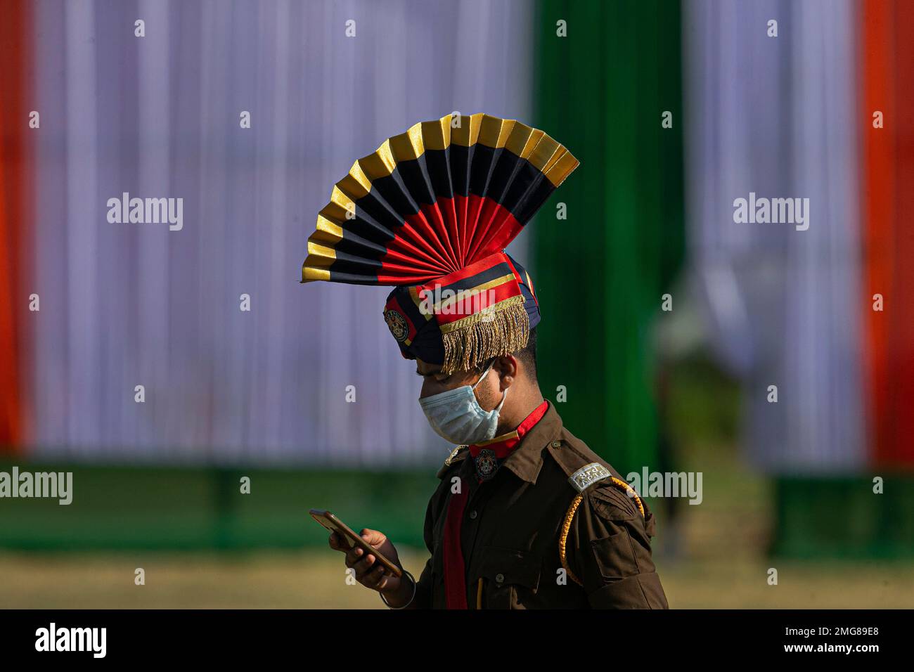 An Indian paramilitary soldier wearing a face mask checks his mobile ...