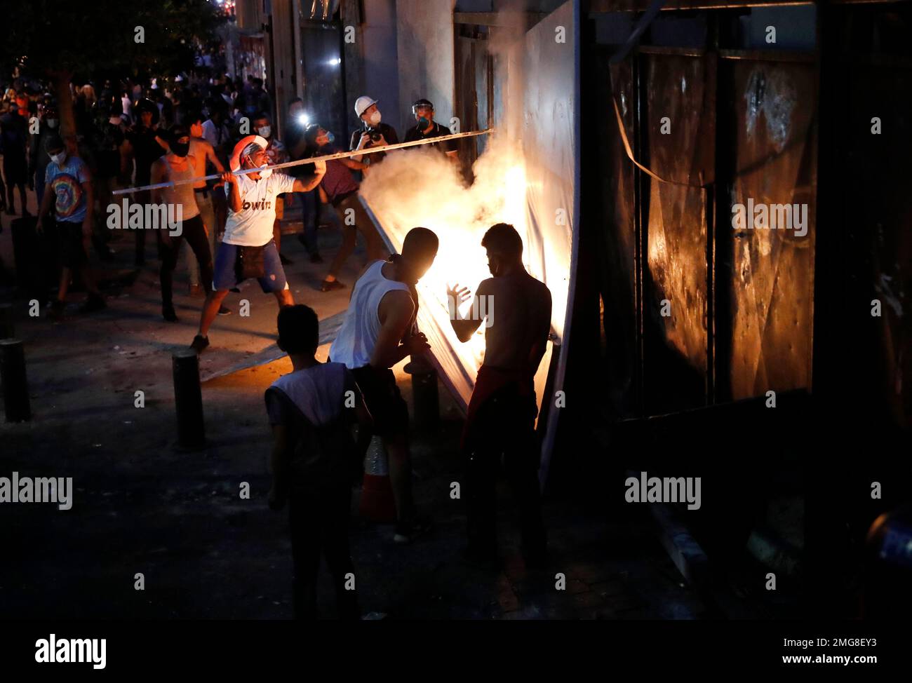 Anti-government protesters burn a plastic board as they try to remove ...