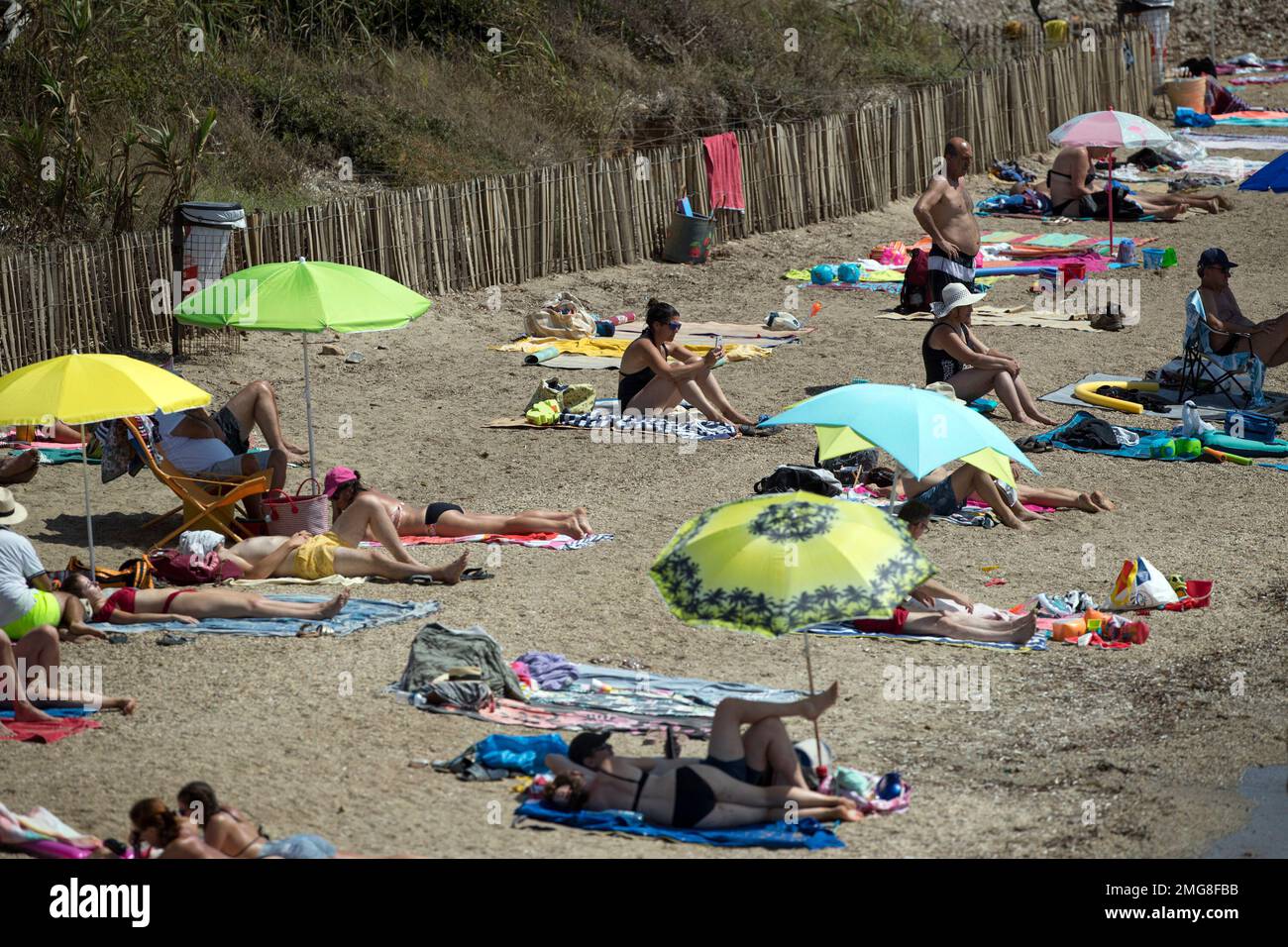 Beachgoers enjoy a hot day in the sun at a beach in Bormes-les-Mimosas ...