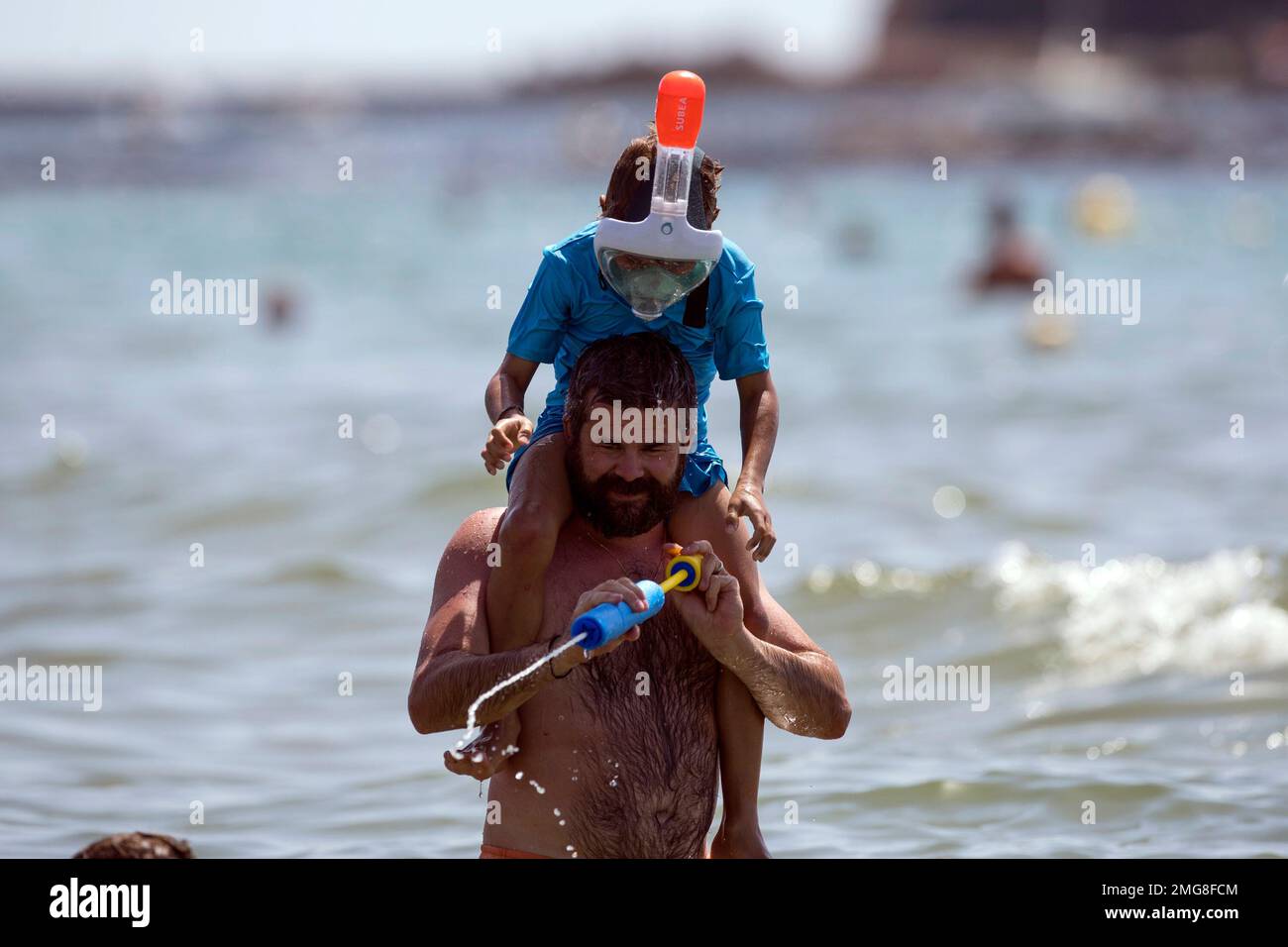Beachgoers enjoy a hot day in the sun at a beach in Bormes-les-Mimosas ...