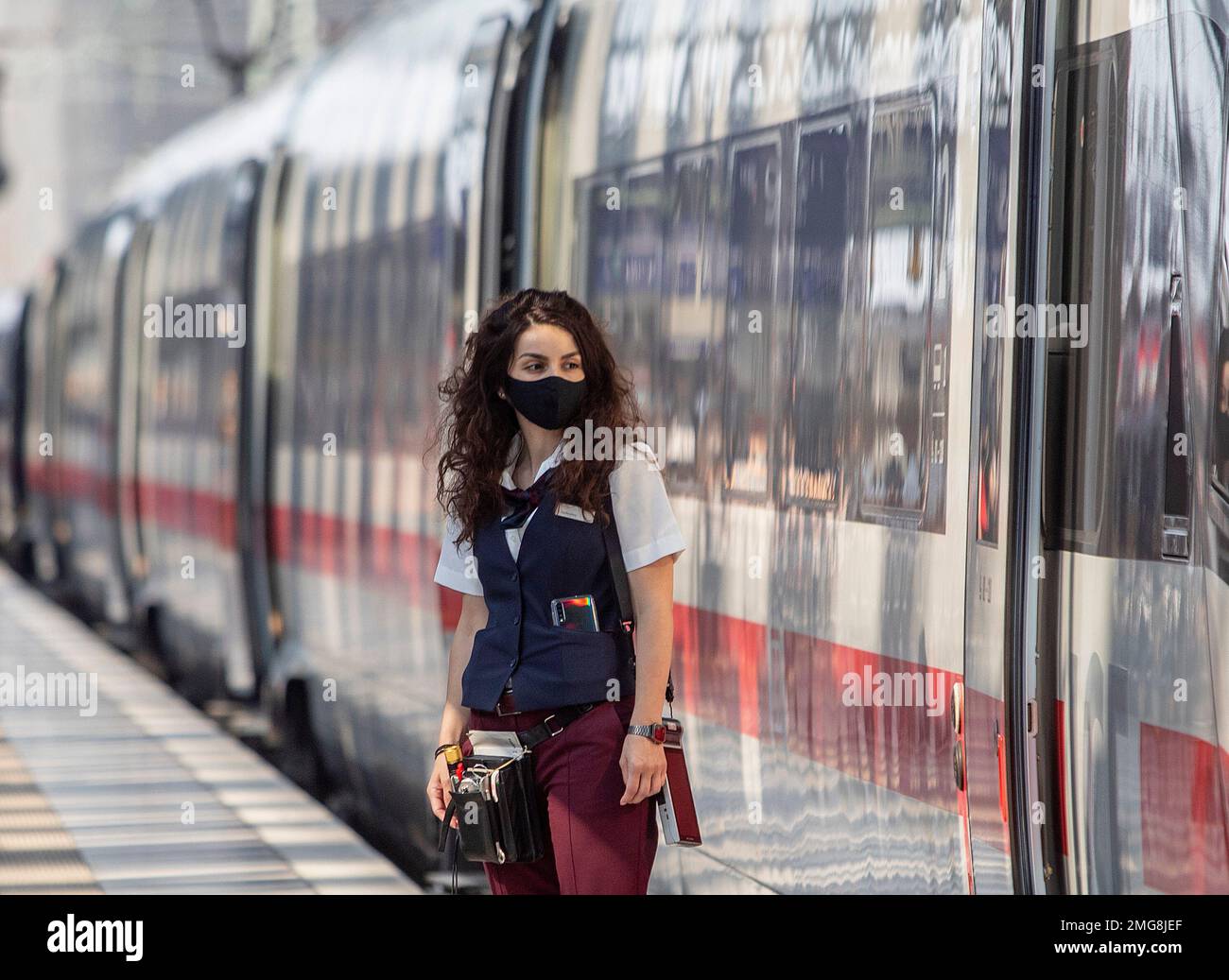 A conductor with face mask waits fo a train to leave the main train ...