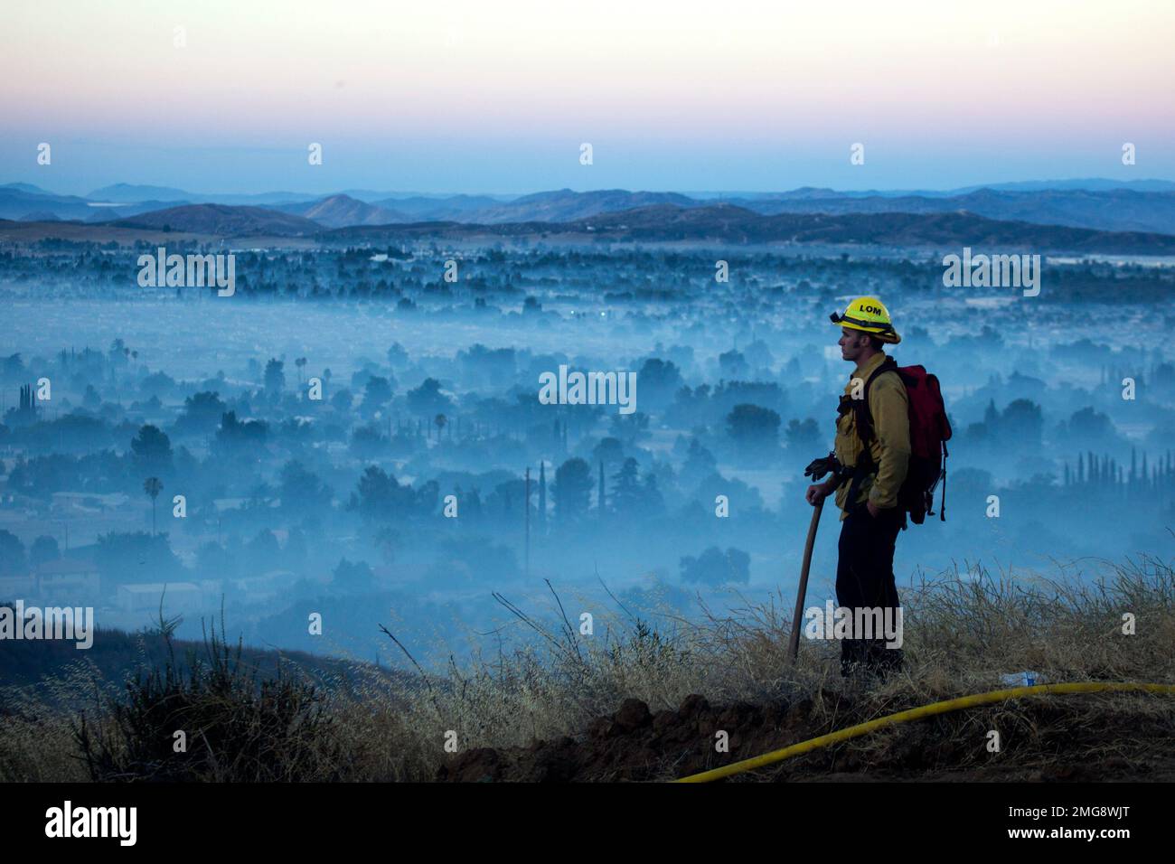 A firefighter watches a brush fire at the Apple Fire in Cherry Valley ...