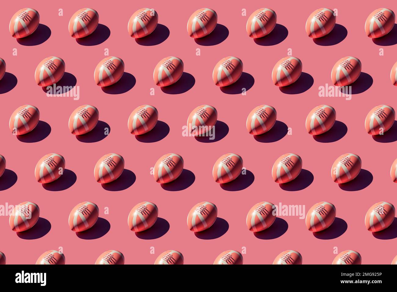 Pattern of pink American football rugby balls with hard shadow on pink ...