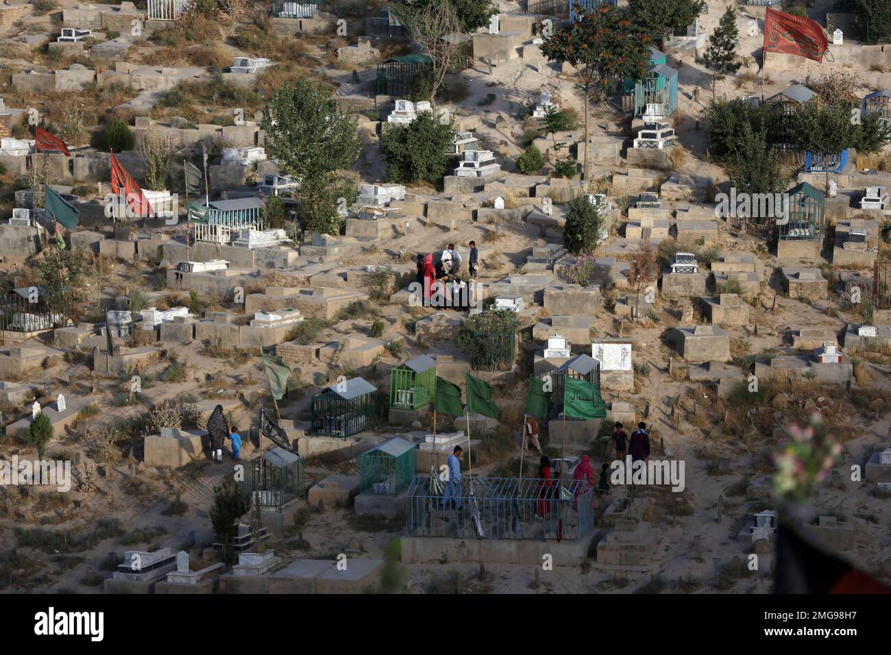 An Afghan family pray next to the grave of a relative at a cemetery on ...