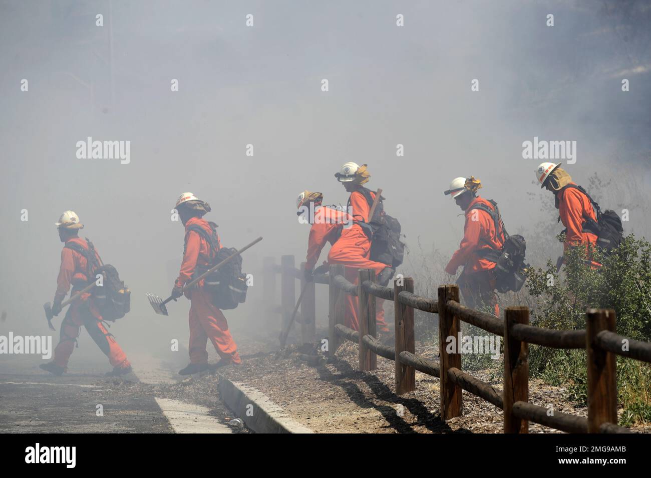 A fire crew walks across a road while fighting the Elsmere Fire on ...