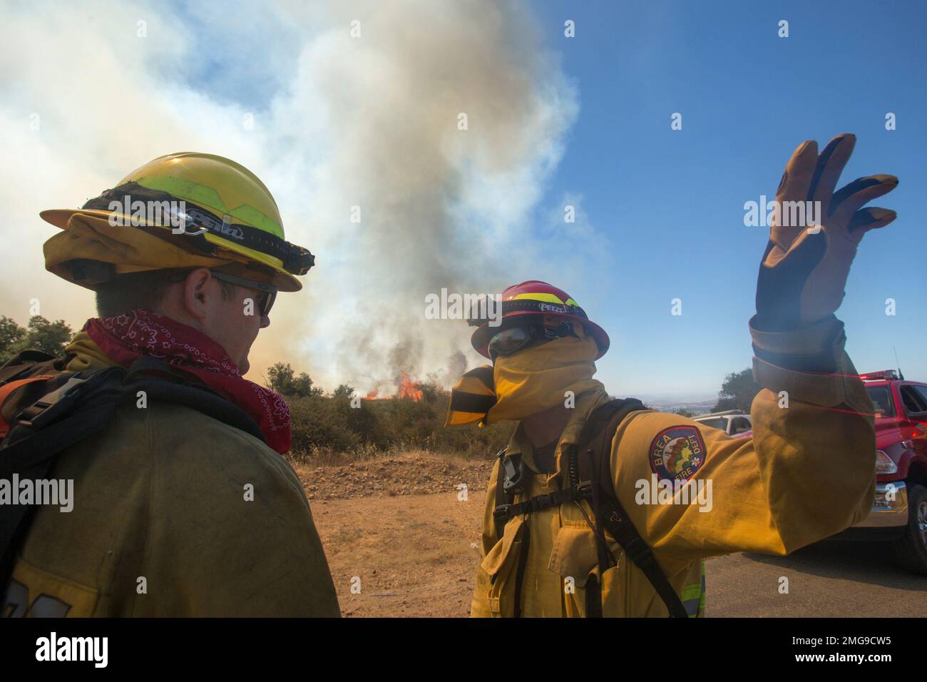 Firefighters watch as smoke rises from the Apple Fire in Cherry Valley ...