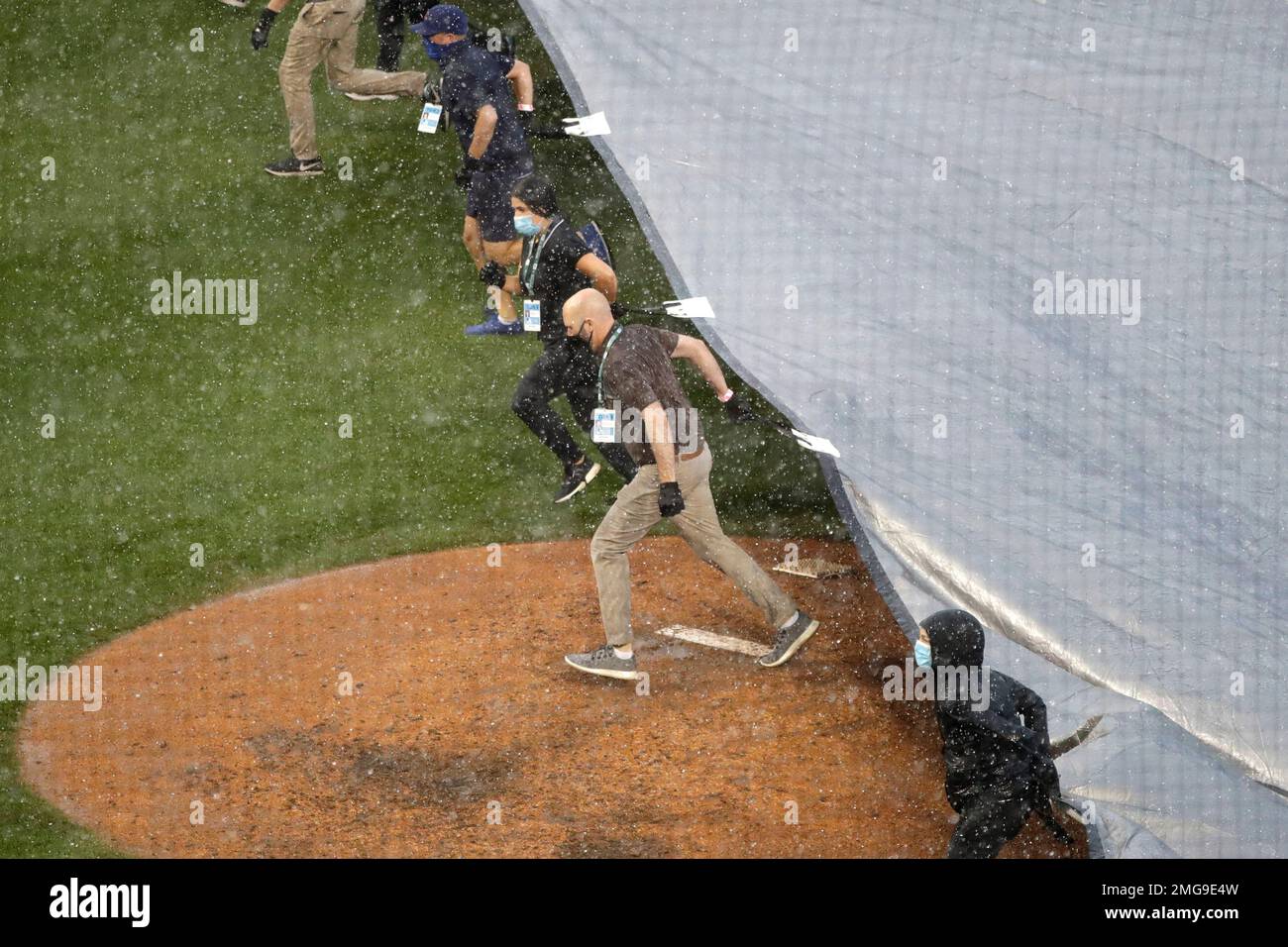 The grounds crew cover the field with a tarp during a rain delay in the ...