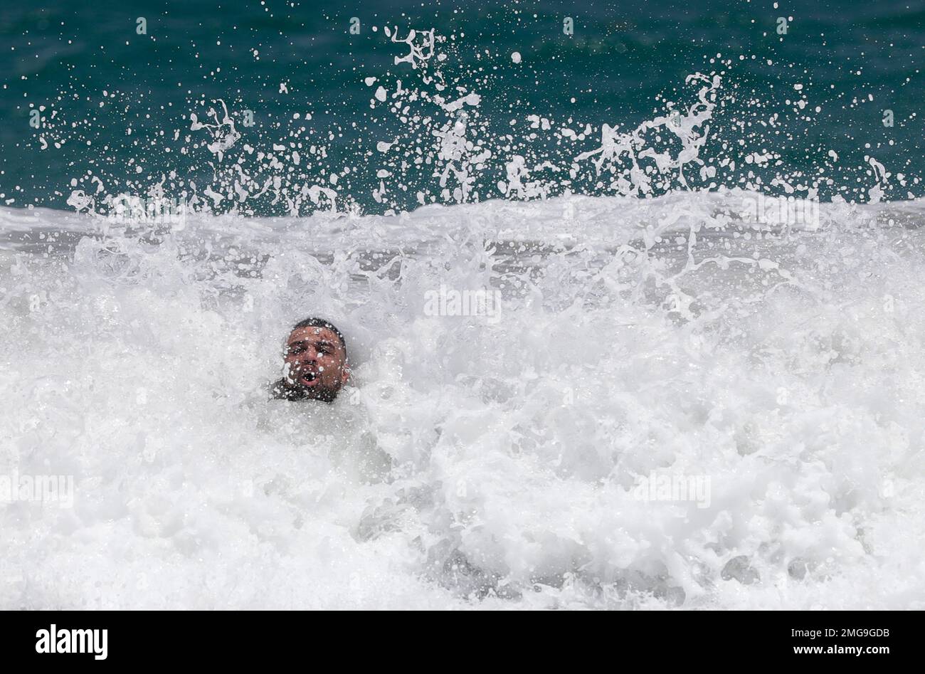 A beach goer is engulfed by a wave as he jumps in the surf, Saturday ...