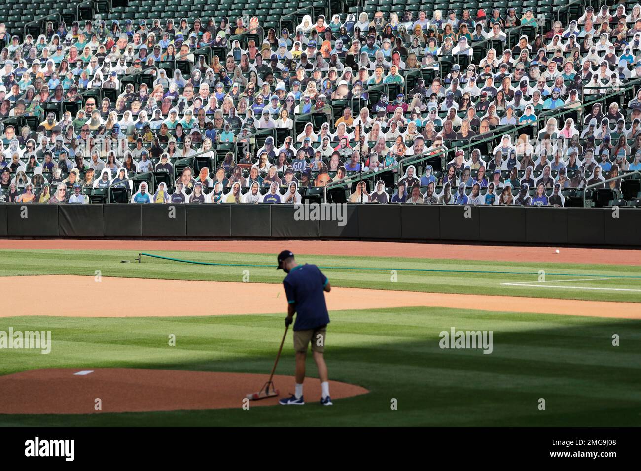 A grounds keeper finishes work on the pitcher's mound in front of ...