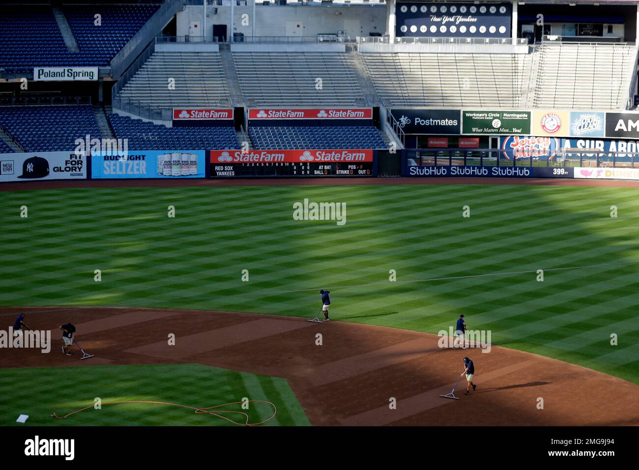 Members of the grounds crew prepare the field before the baseball game ...