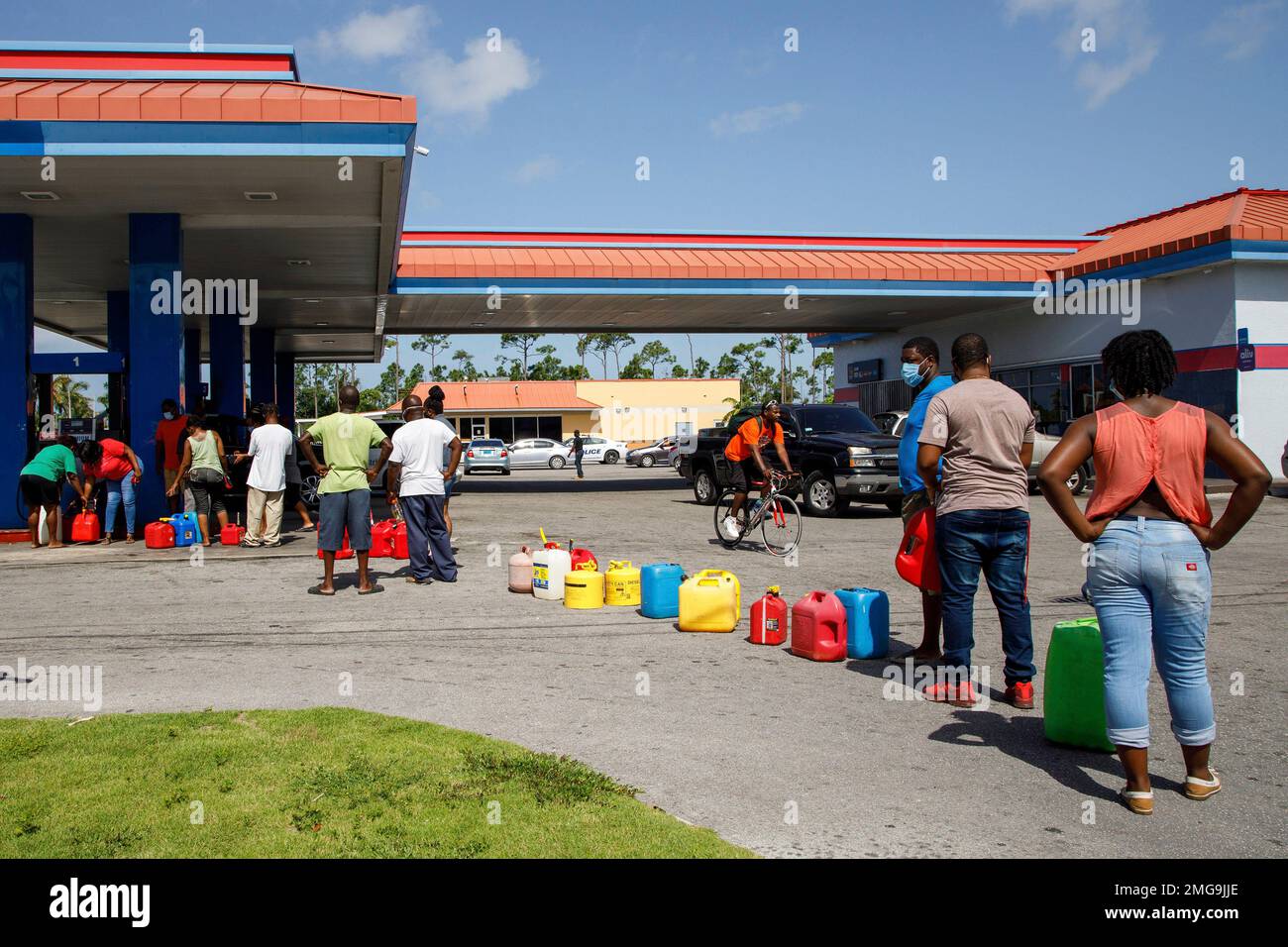 Residents wait in line to fill their containers with gasoline before ...