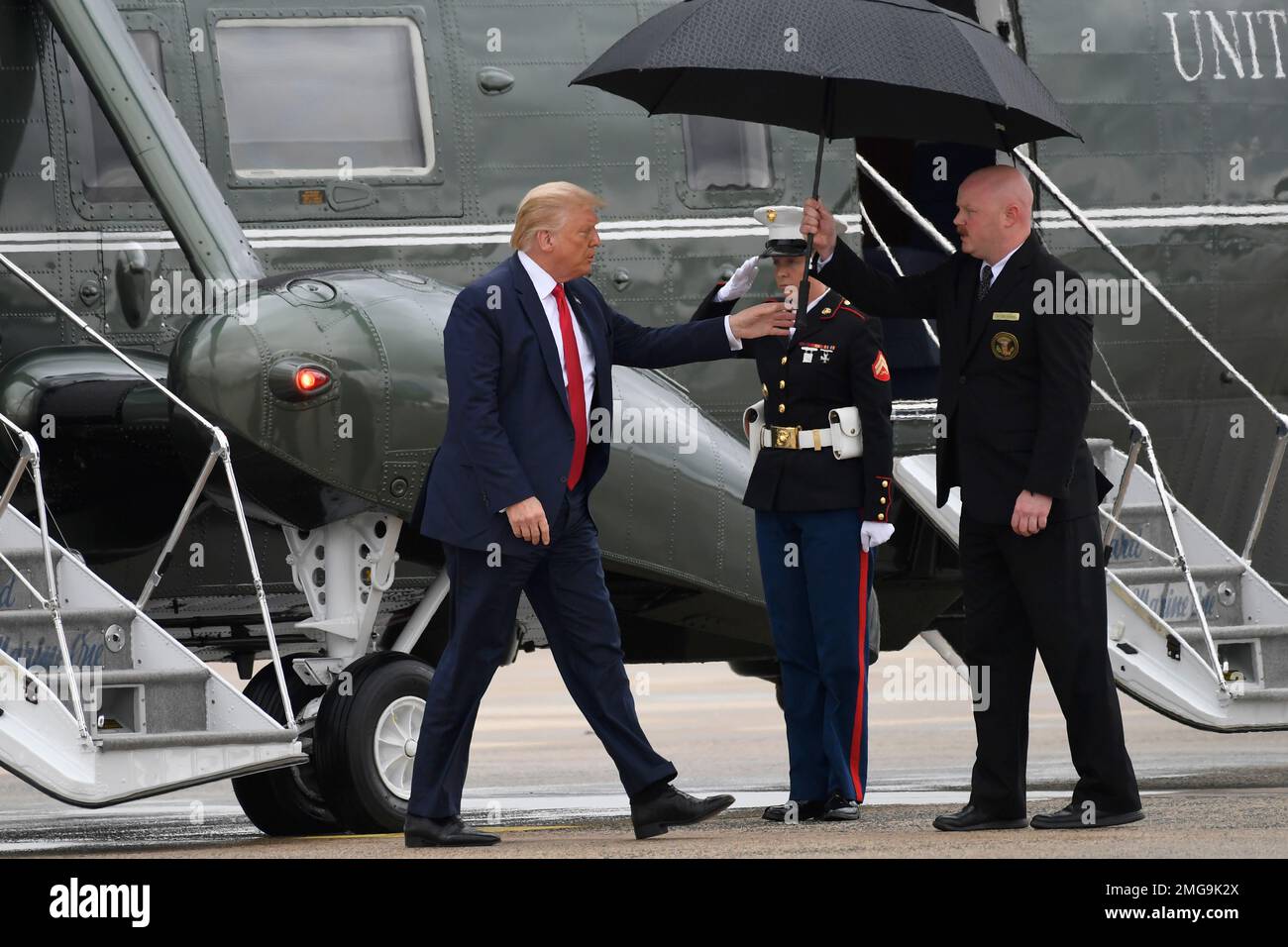 President Donald Trump is handed an umbrella as he steps off of Marine ...