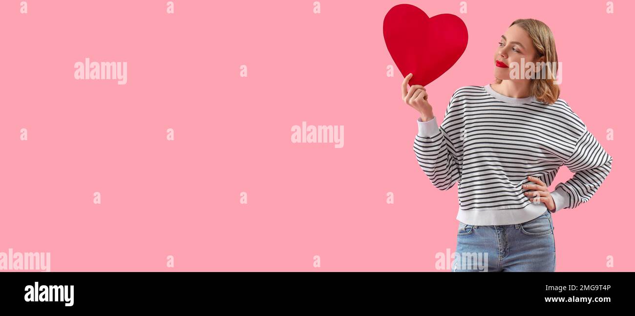 Beautiful young woman holding red paper heart on pink background with ...