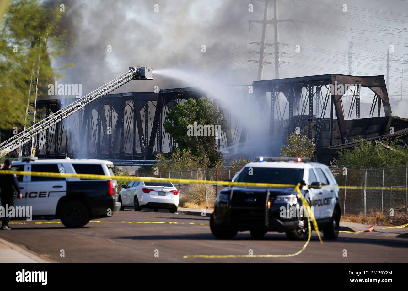 Police cars block off a street as firefighters attempt to put out a ...