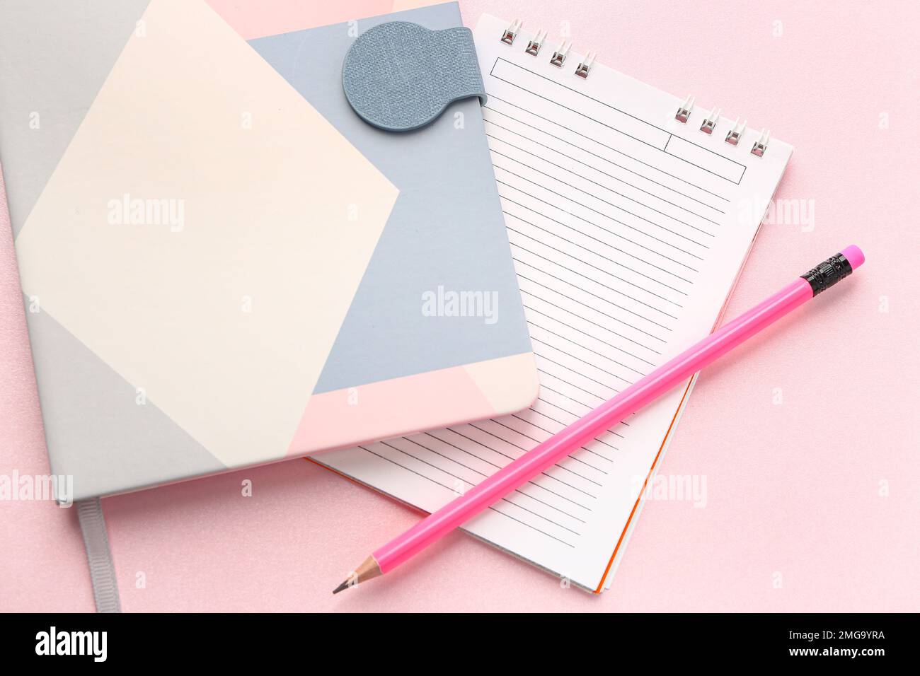Notebooks and pencil on pink background, closeup Stock Photo - Alamy