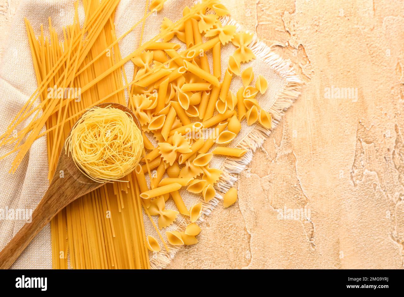 Different types of uncooked pasta on color table Stock Photo - Alamy
