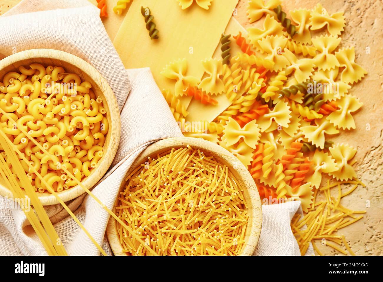 Composition with bowls of different types of raw pasta on color ...