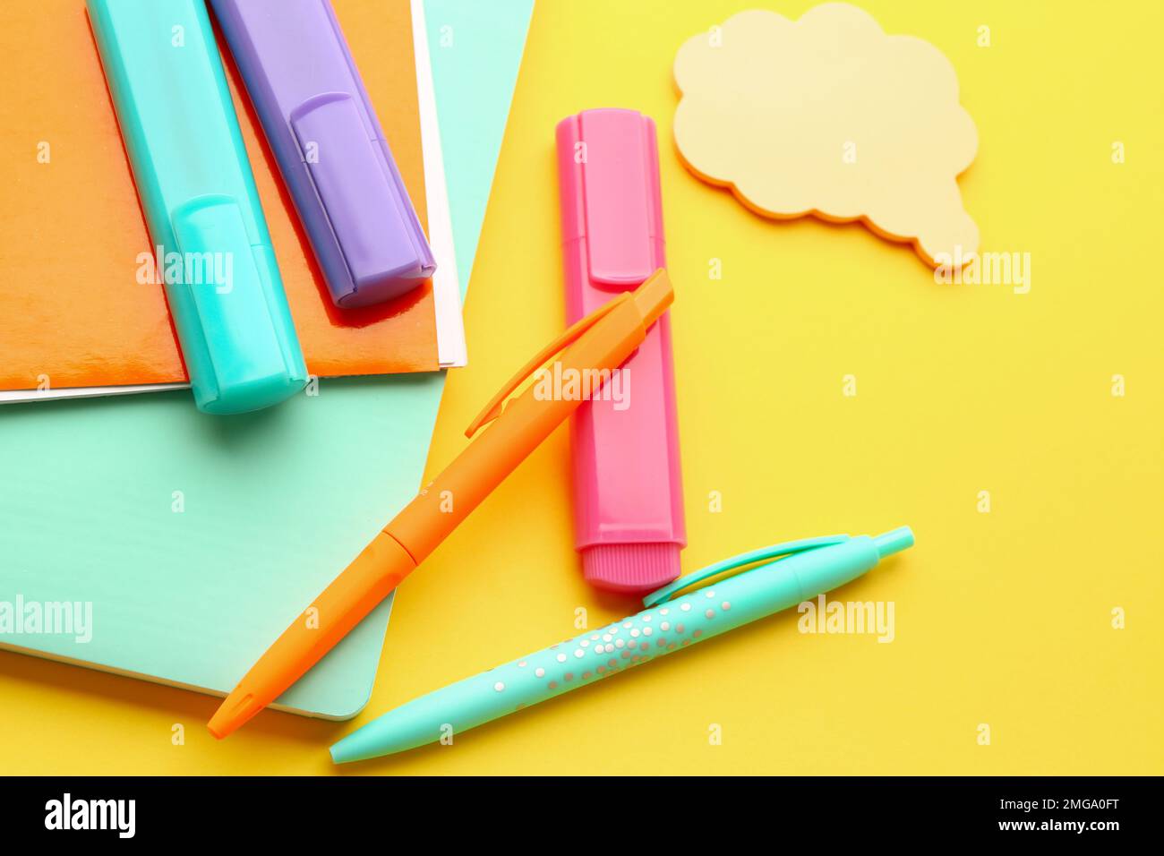 Notebooks, pens, markers and sticky notes on yellow background, closeup ...