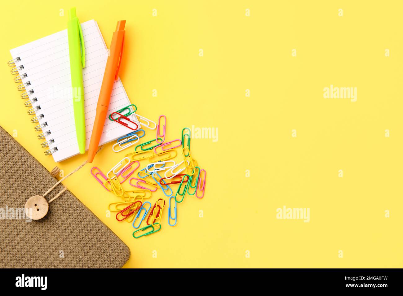 Notebooks, pens and paper clips on yellow background Stock Photo - Alamy