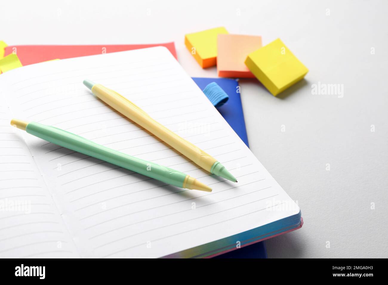 Notebooks, pens and sticky notes on light background, closeup Stock ...