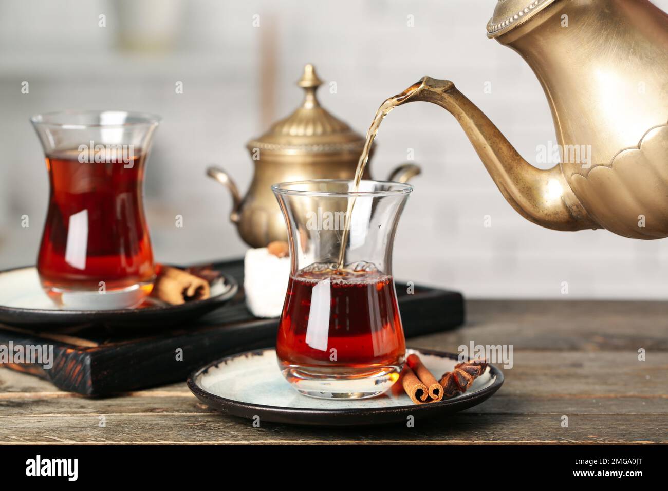 Pouring of hot Turkish tea from teapot into glass on wooden table Stock ...