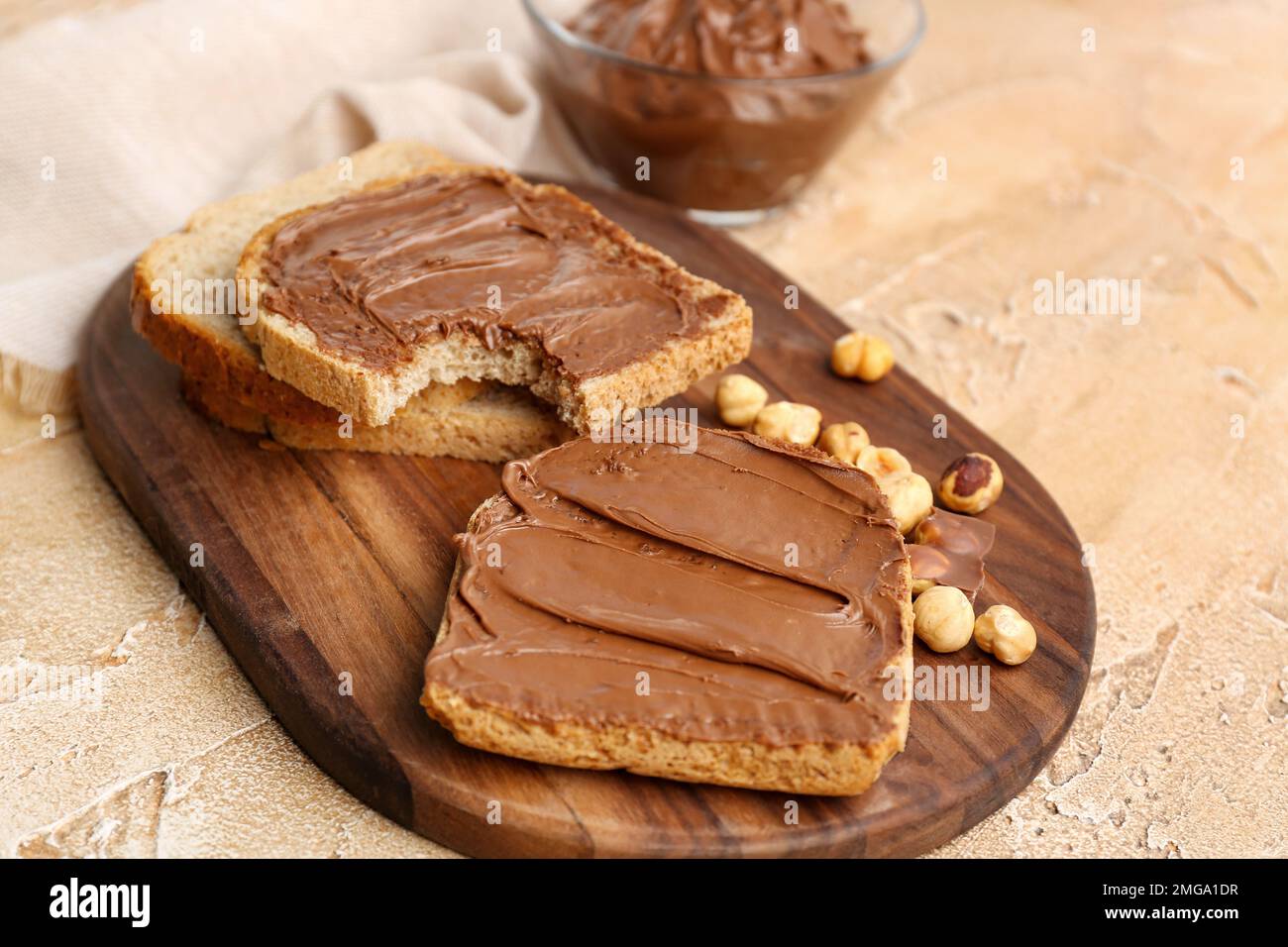 Wooden board of tasty toasts with hazelnut butter and nuts on color ...